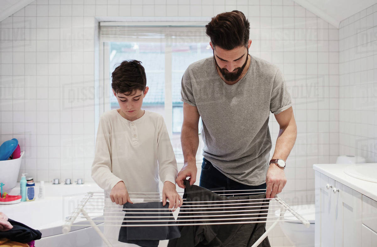 Father and son drying clothes on rack at home - Royalty-free Stock ...