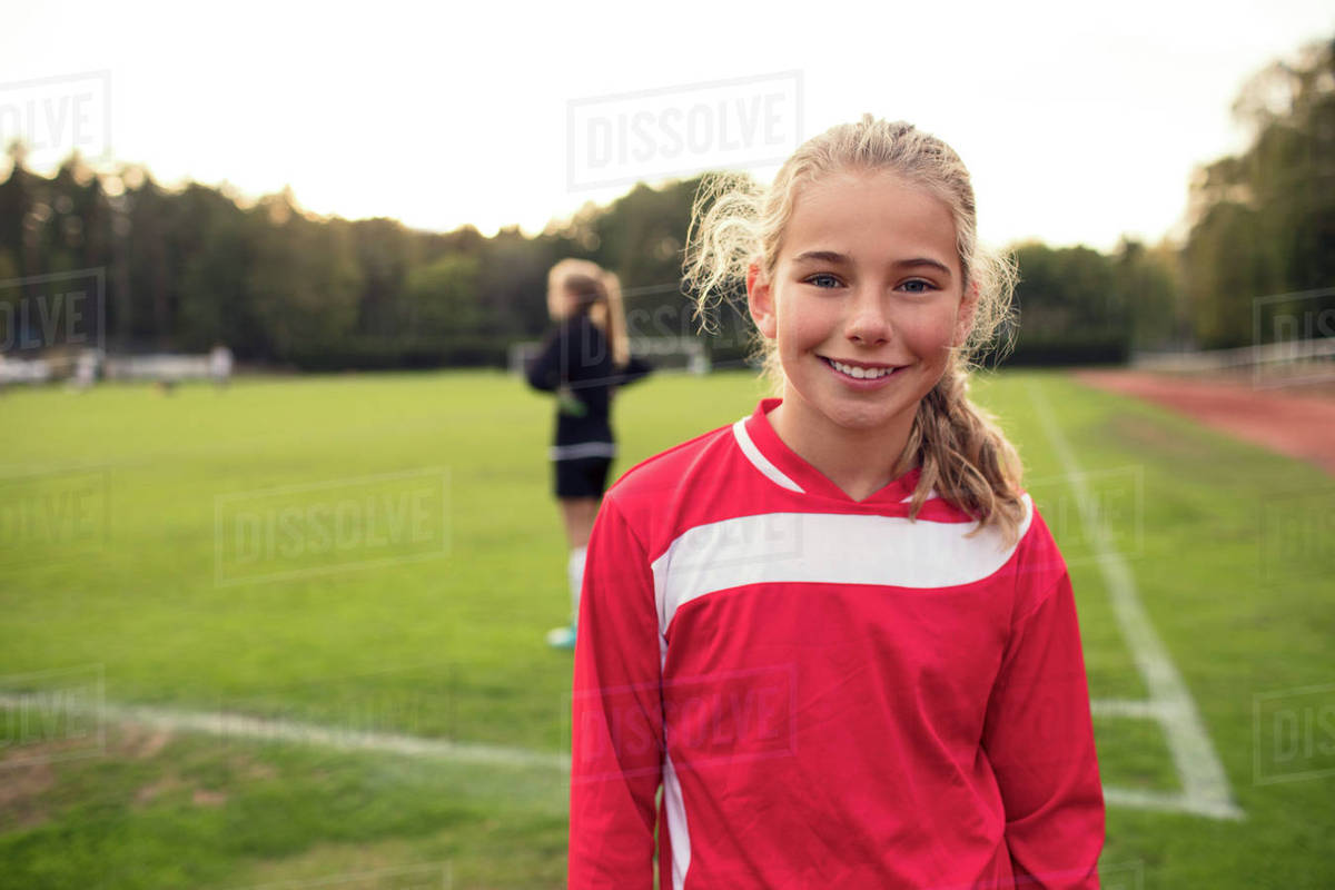 Portrait of happy soccer girl standing on field - Stock Photo - Dissolve