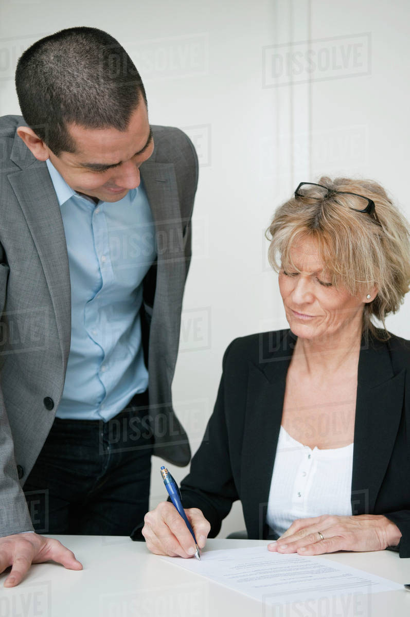Two colleagues signing paper - Stock Photo - Dissolve