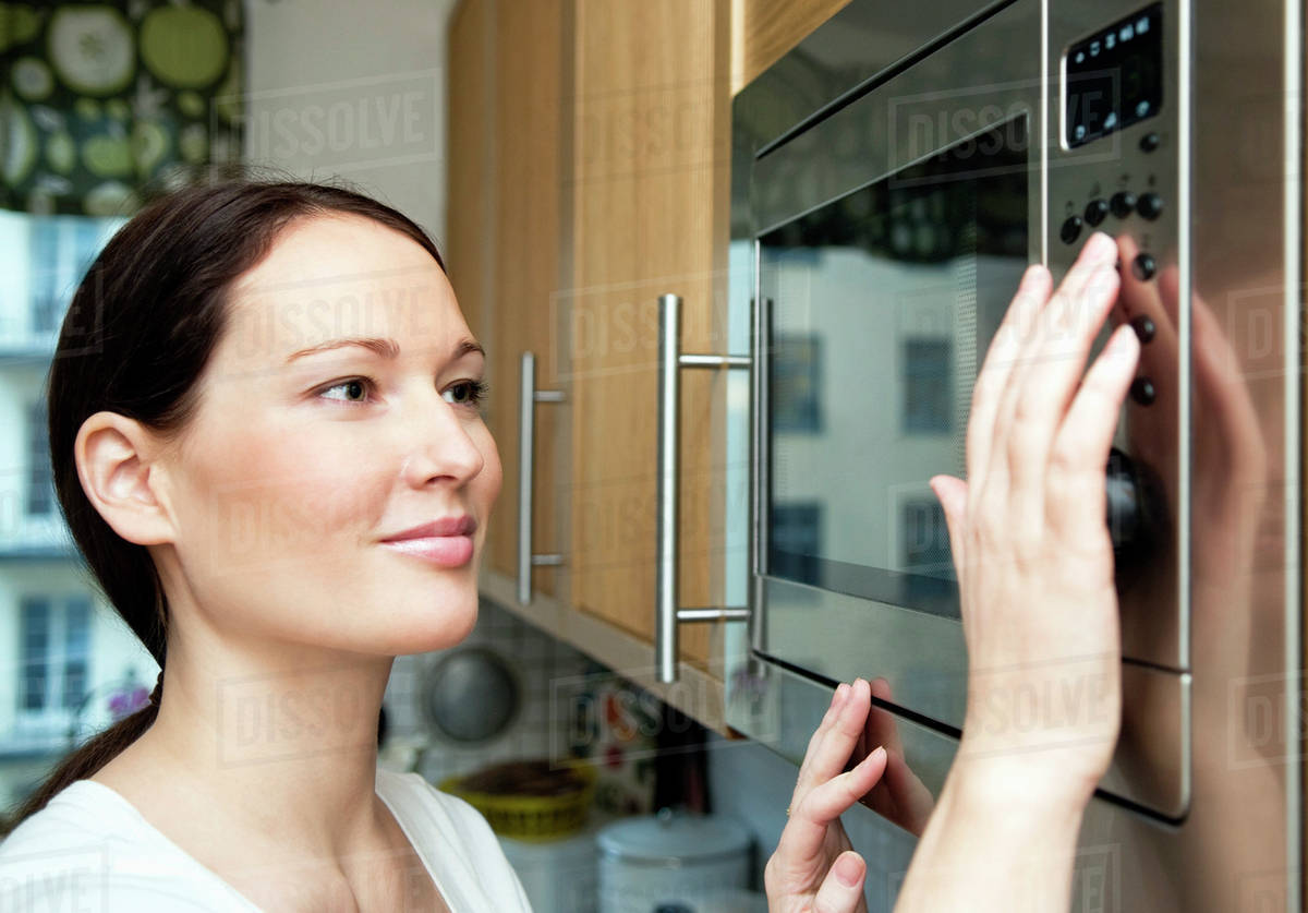 Woman using microwave oven - Royalty-free Stock Photo | Dissolve