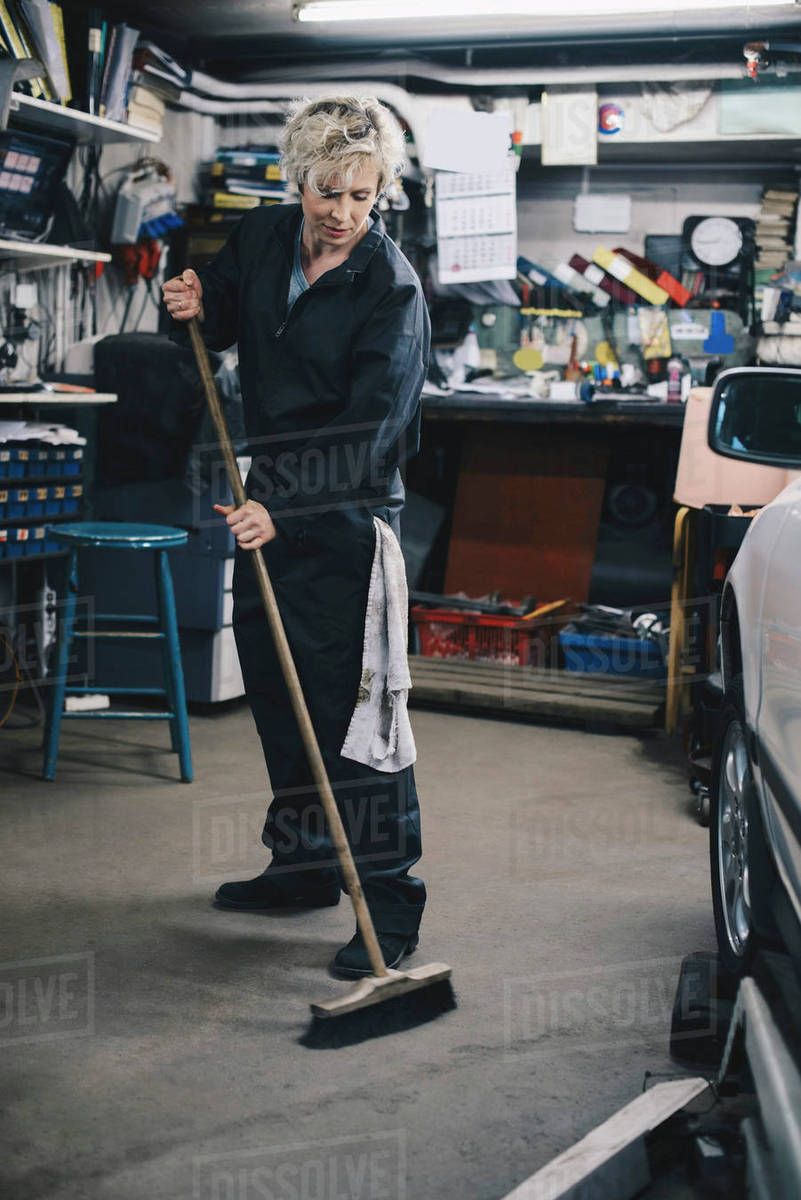 Full length of female mechanic sweeping in auto repair shop - Royalty ...