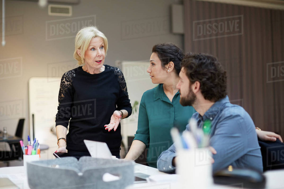 Senior female professional talking with colleagues at creative office ...