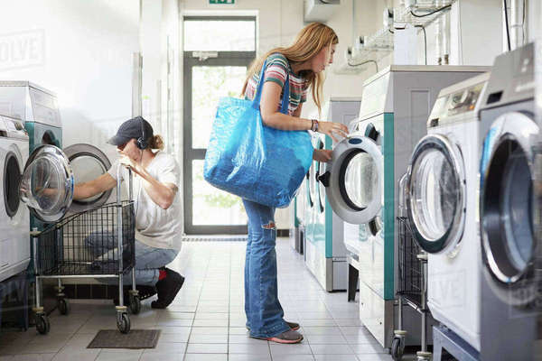 Full length of male and female university students doing laundry at ...