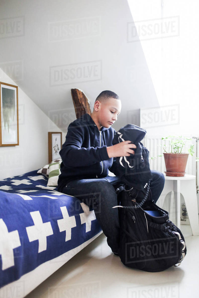 Teenage boy packing clothes into backpack in bedroom at home - Stock ...