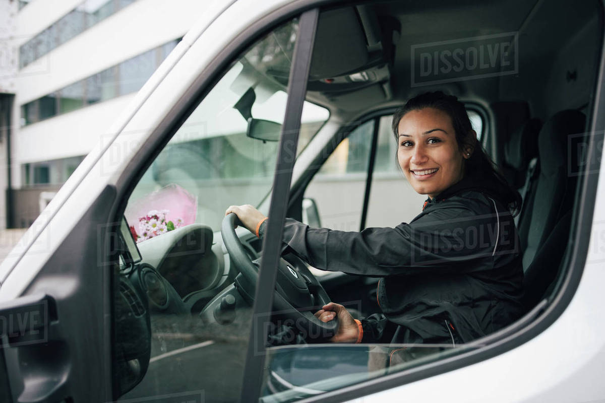 Portrait of smiling woman driving delivery van in city - Royalty-free ...