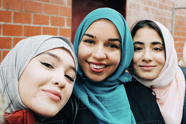 Portrait of smiling Muslim female friends against building in city ...