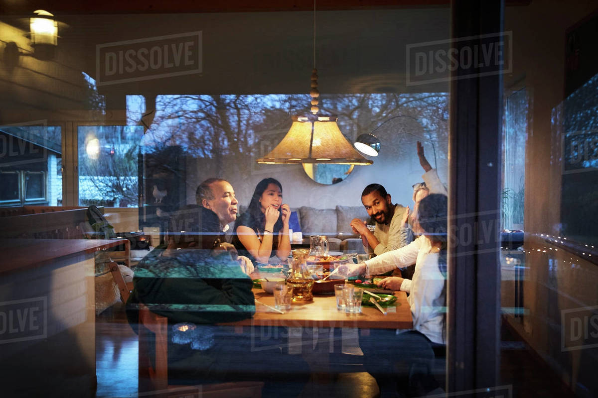 Multi-generation family talking while having dinner at table seen ...