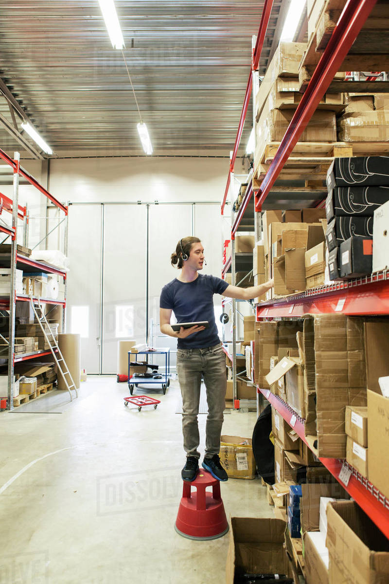 Manual worker analyzing boxes while using digital tablet in ...