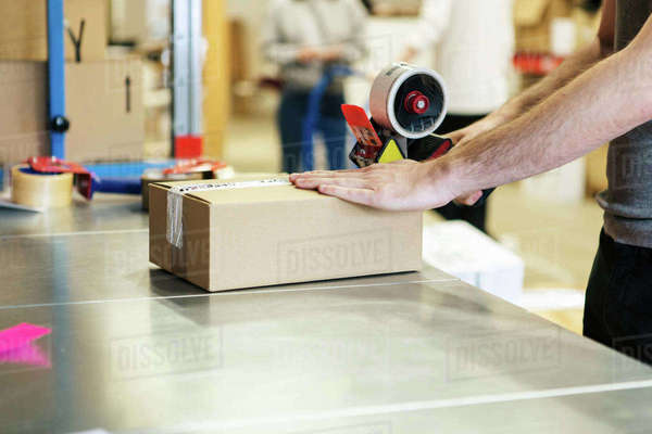 Midsection of man packing box in distribution warehouse - Royalty-free ...