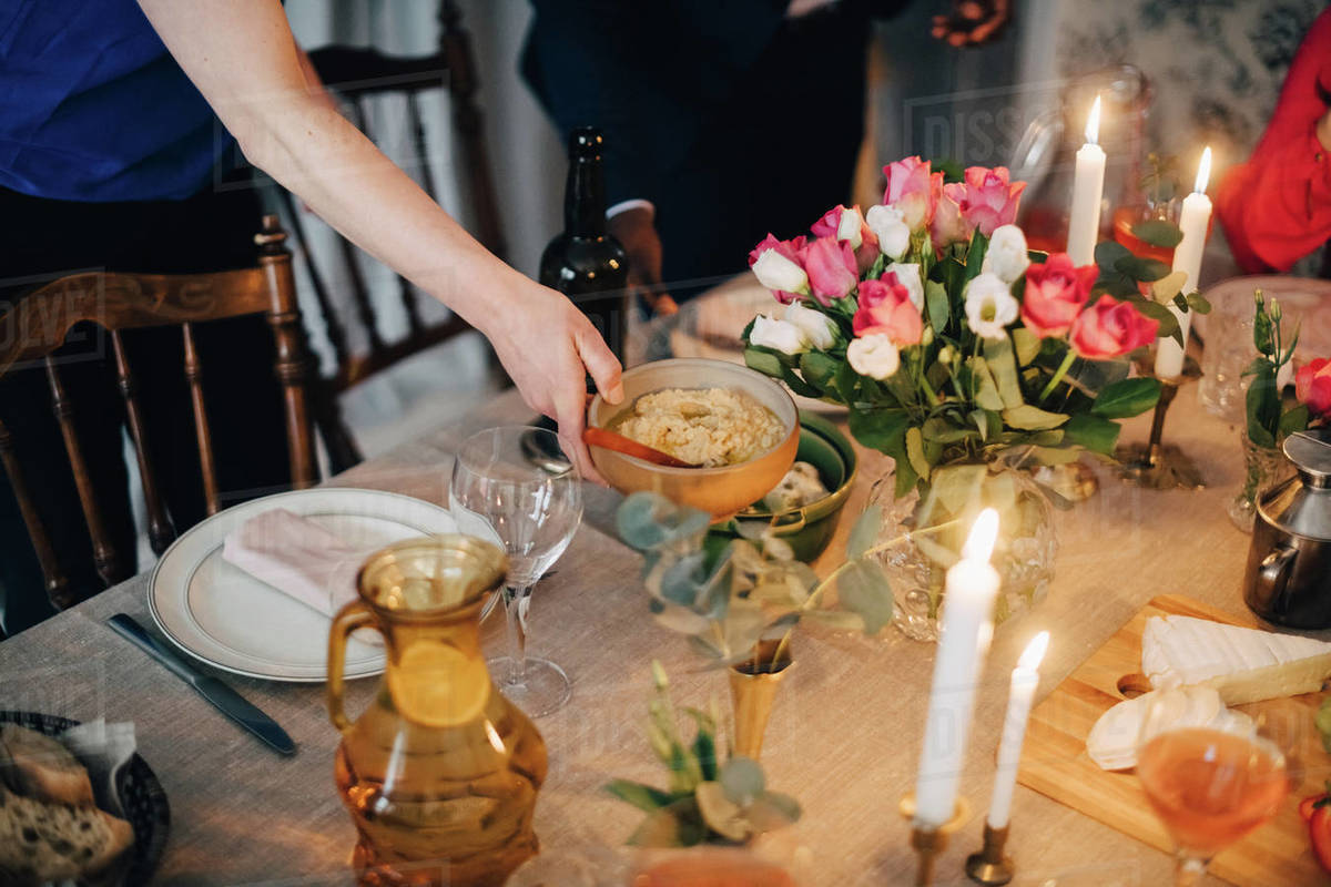 Cropped hand of woman arranging food on dining table at dinner party ...