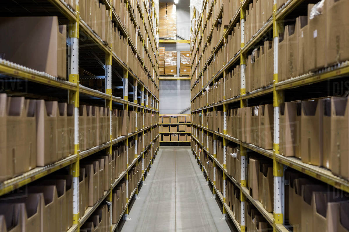 Empty narrow aisle amidst racks at warehouse - Royalty-free Stock Photo ...