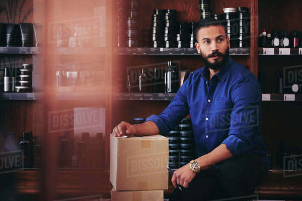 Salesman looking away while kneeling by boxes in deli - Royalty-free ...