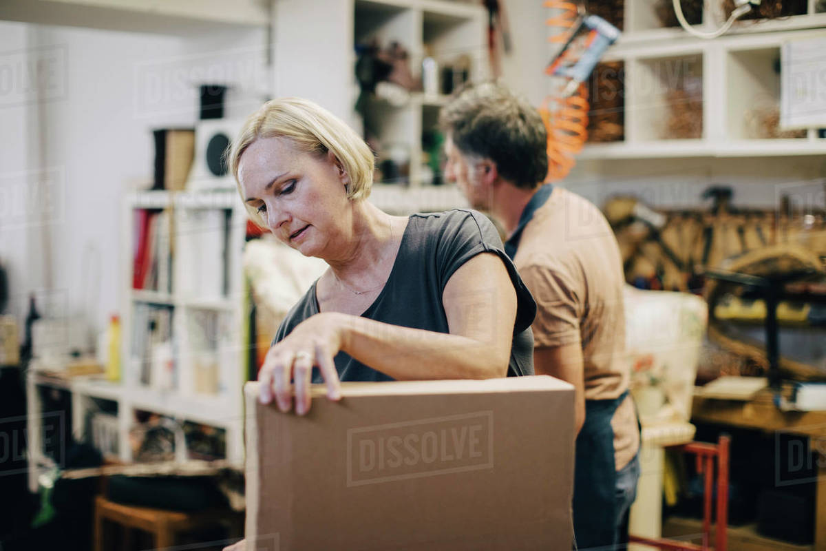 Female craftsperson with cardboard box in workshop - Royalty-free Stock ...