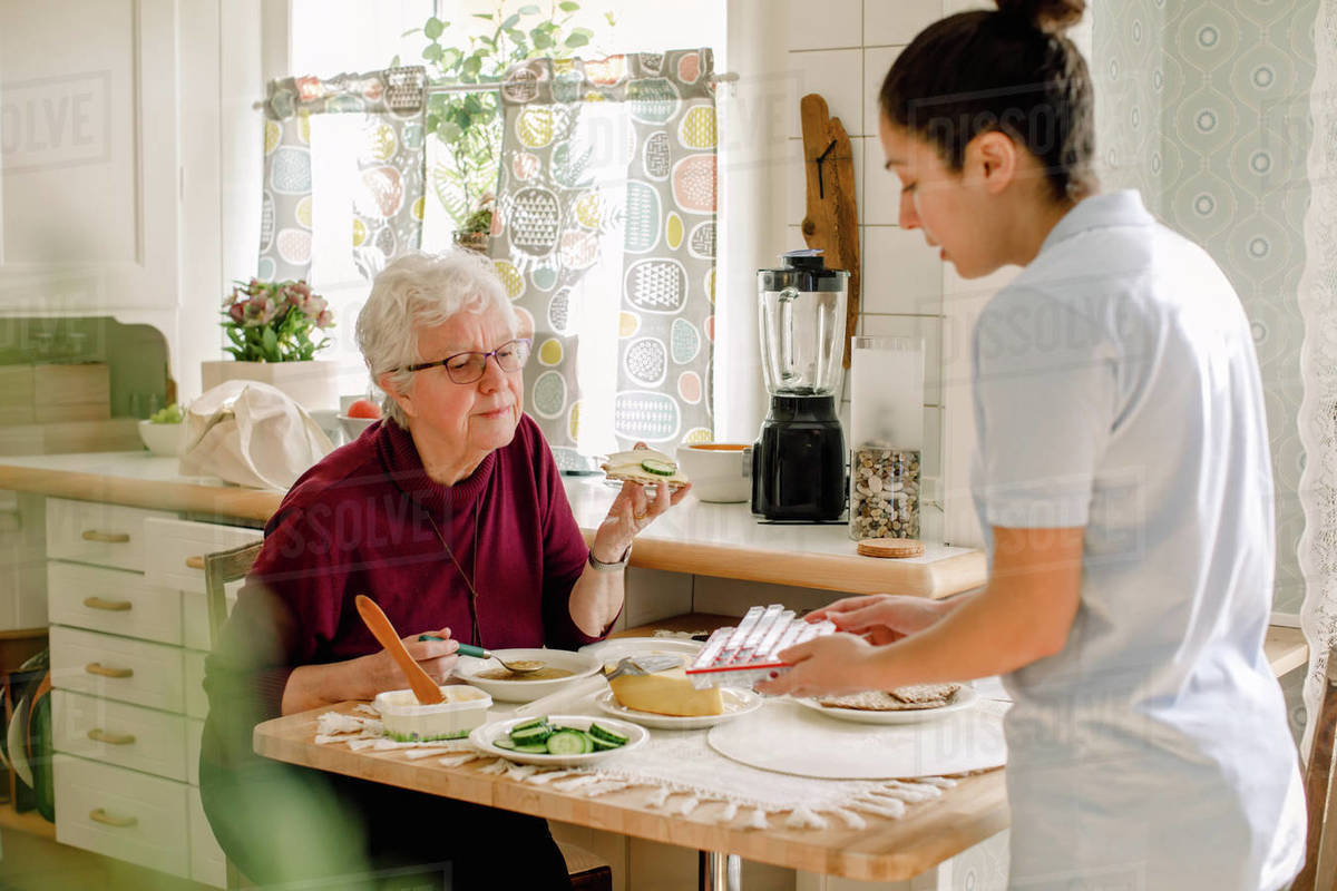 Female healthcare worker explaining medicine to senior woman eating ...