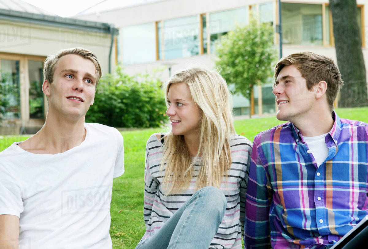 Three students sitting on the lawn - Royalty-free Stock Photo | Dissolve