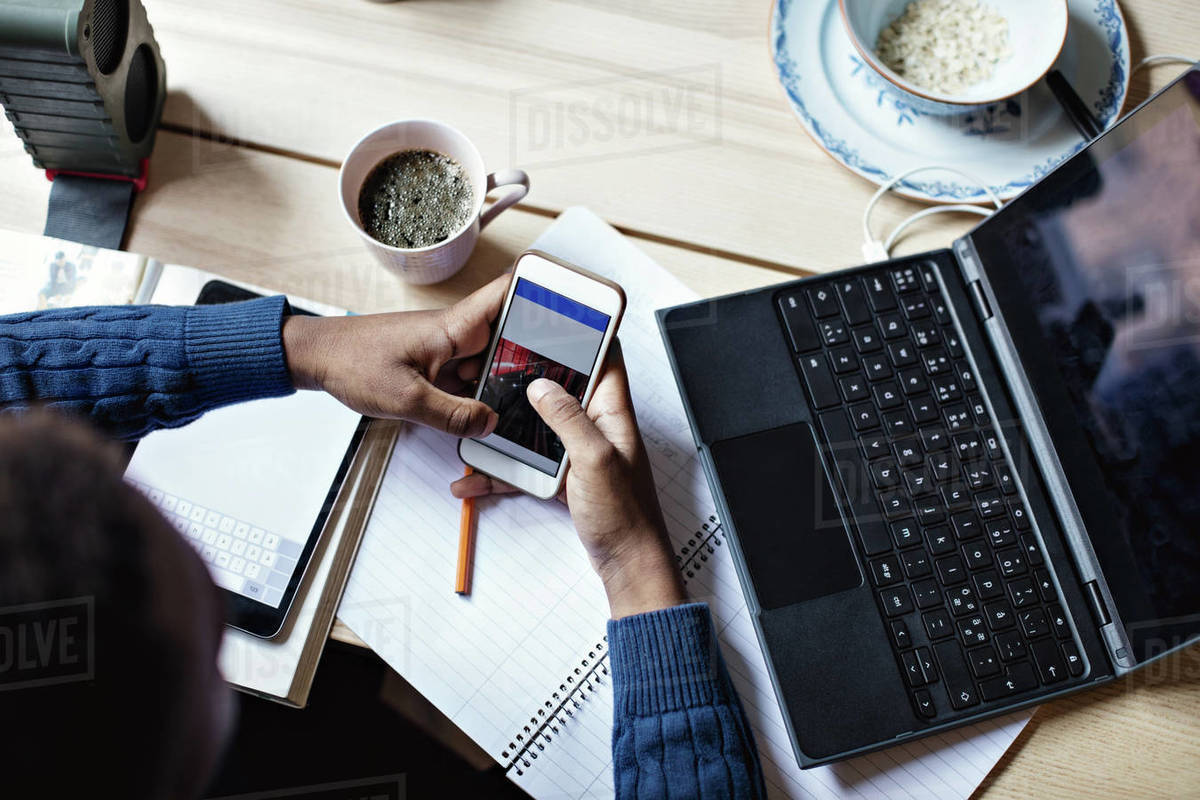 High angle view of teenage boy using mobile phone while studying on ...