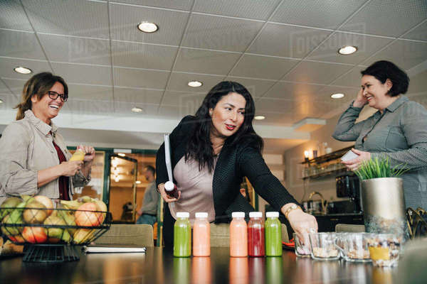 Smiling businesswoman taking food from table during conference event at ...