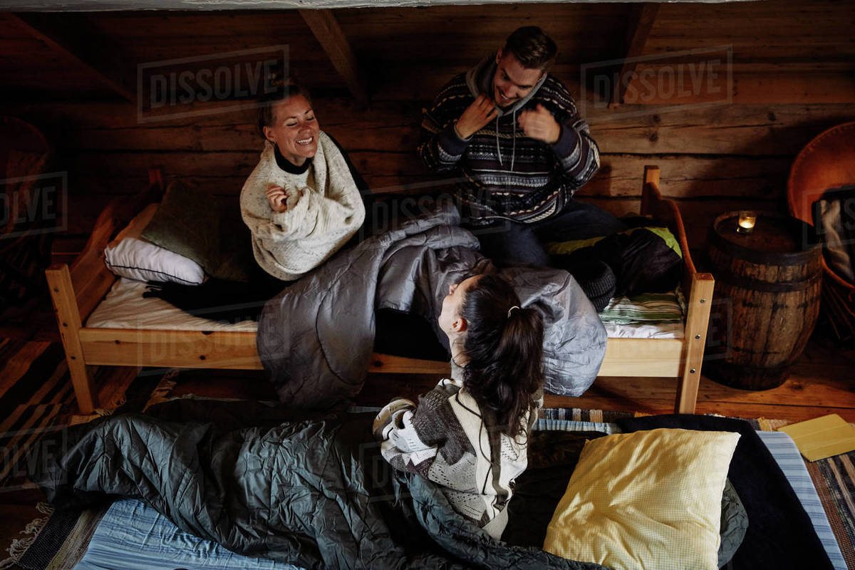 High angle view of smiling friends talking while resting in cottage at bedtime - Royalty-free ...