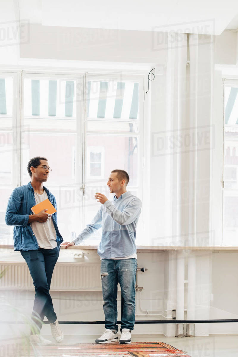 Full Length of computer programmers standing by window in office ...