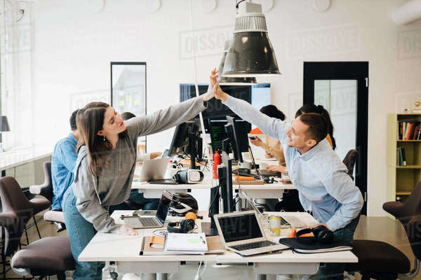 Happy male and female computer programmers doing high-five over ...