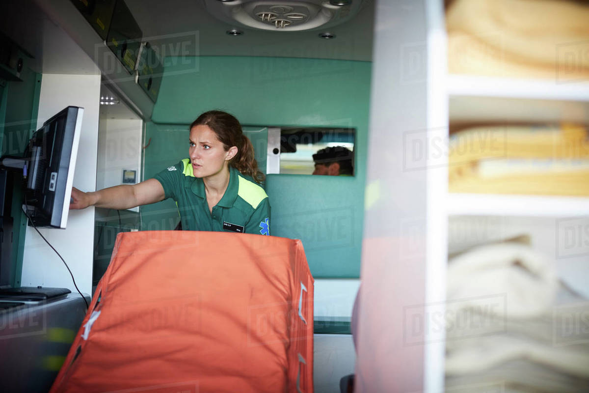 Female paramedic reading monitoring equipment screen in ambulance ...