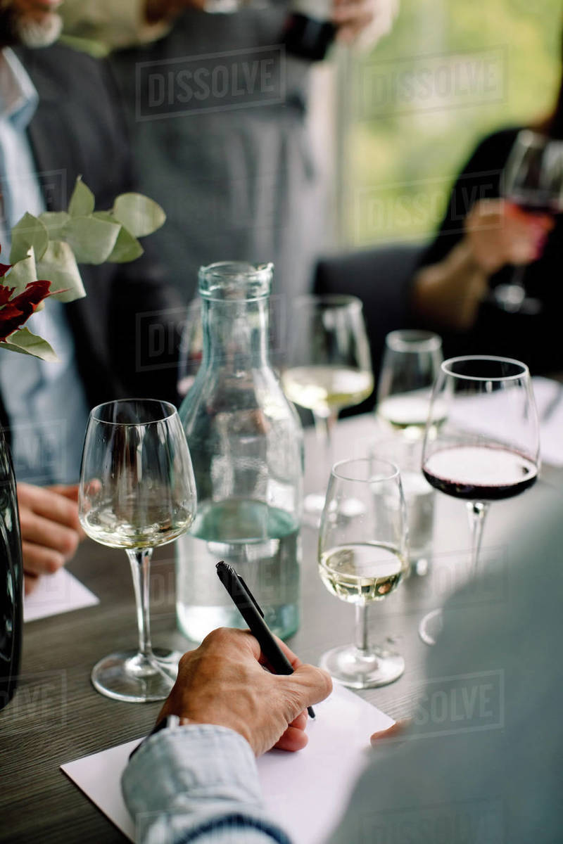 Cropped image of businessman writing on document at table in convention ...