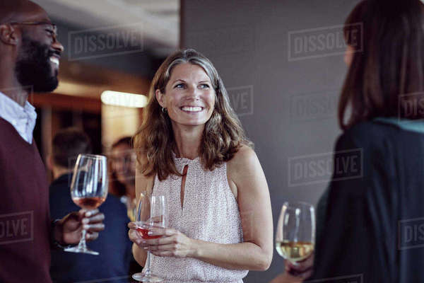 Smiling business people talking over drinks in office party - Royalty ...