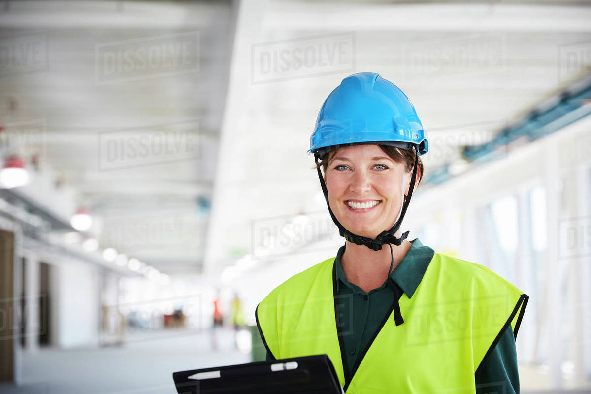 Portrait of smiling female construction manager in reflective clothing ...