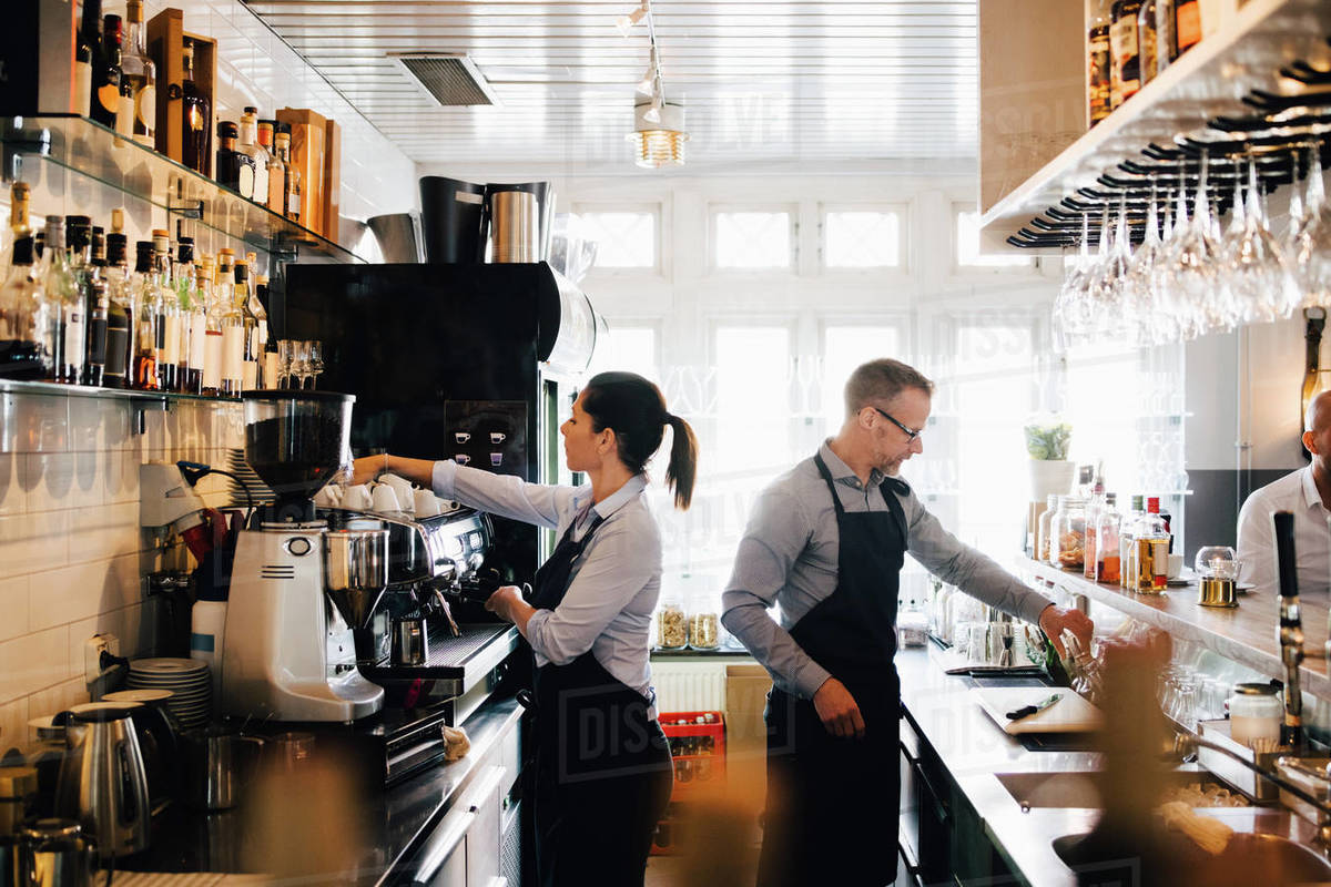 Male and female coworkers working in kitchen at restaurant - Royalty ...