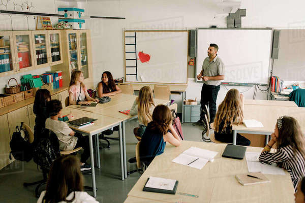 Male tutor teaching students in classroom - Royalty-free Stock Photo ...