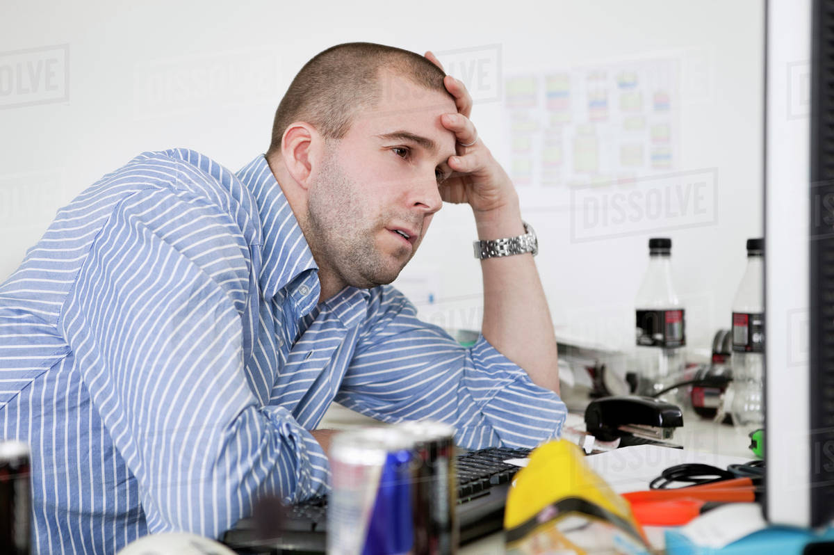 Tired man sitting by computer - Royalty-free Stock Photo | Dissolve