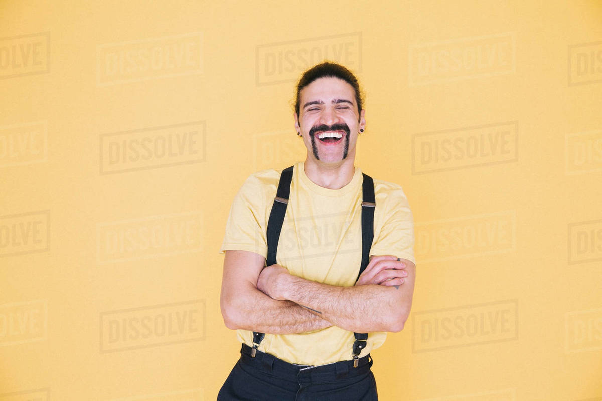 Happy man standing against yellow background - Stock Photo - Dissolve