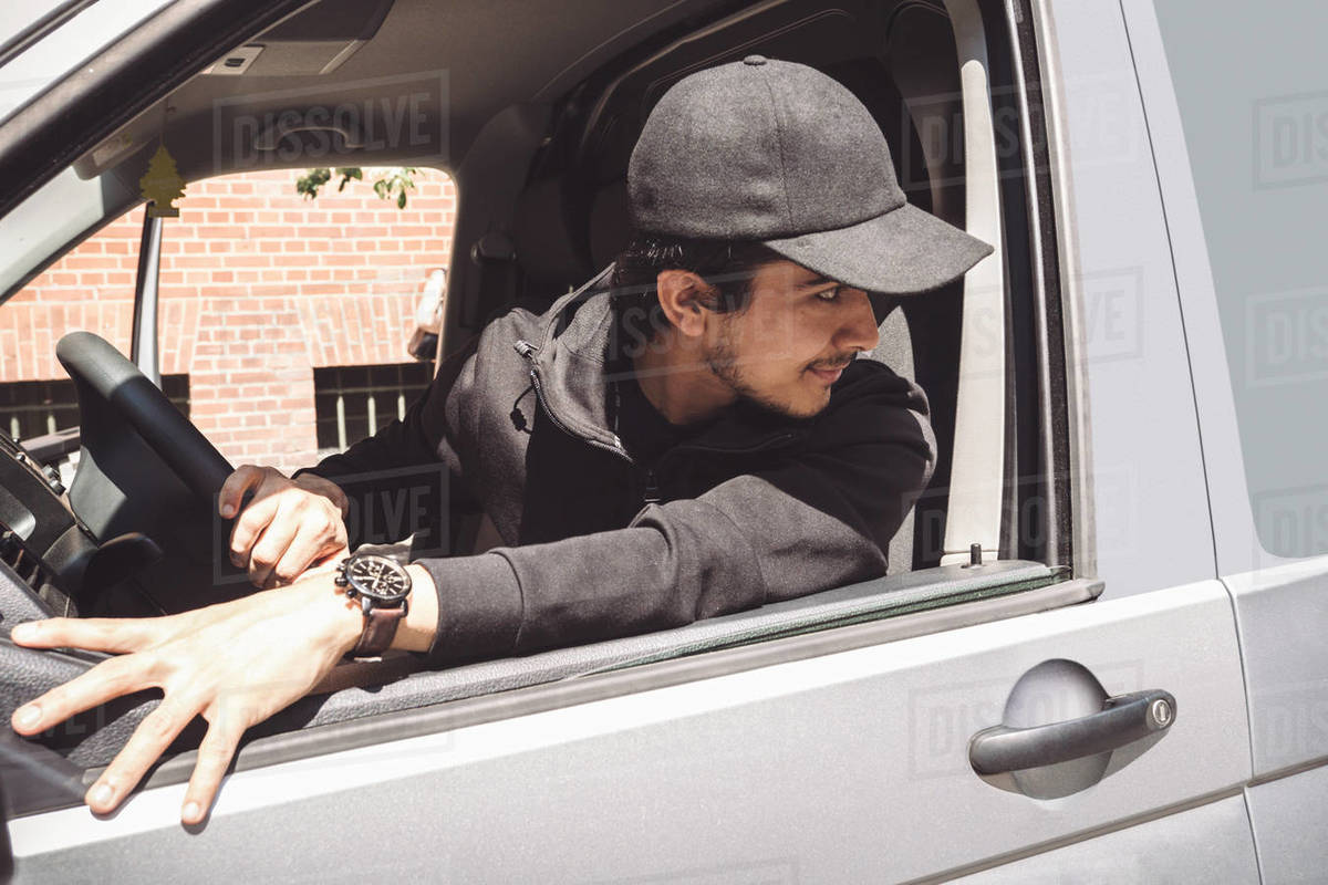 Delivery man looking through window while driving truck - Royalty-free ...