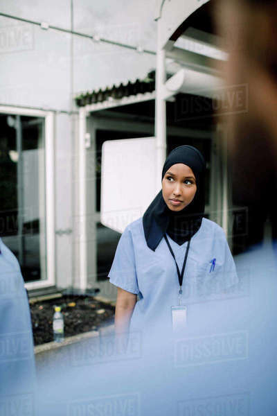 Contemplating female nurse looking at colleague in hospital - Royalty ...