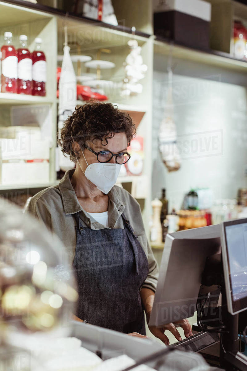 Female store owner working on computer in deli store - Stock Photo ...