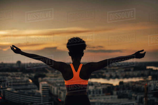 Female athlete with arms outstretched exercising during sunset - Stock ...