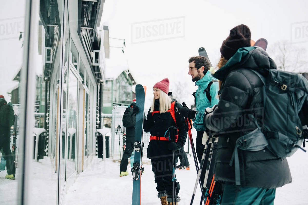 Male and female friends standing outside store during winter - Stock ...
