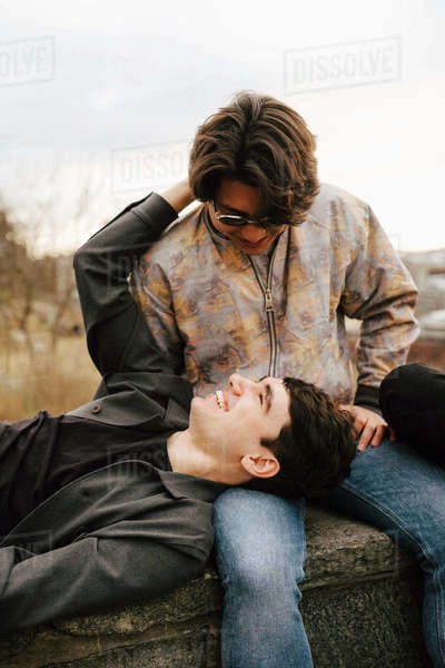 Male friends talking with each other on retaining wall - Royalty-free ...