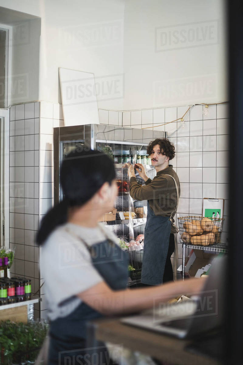 Male and female colleagues talking while working in store - Stock Photo ...