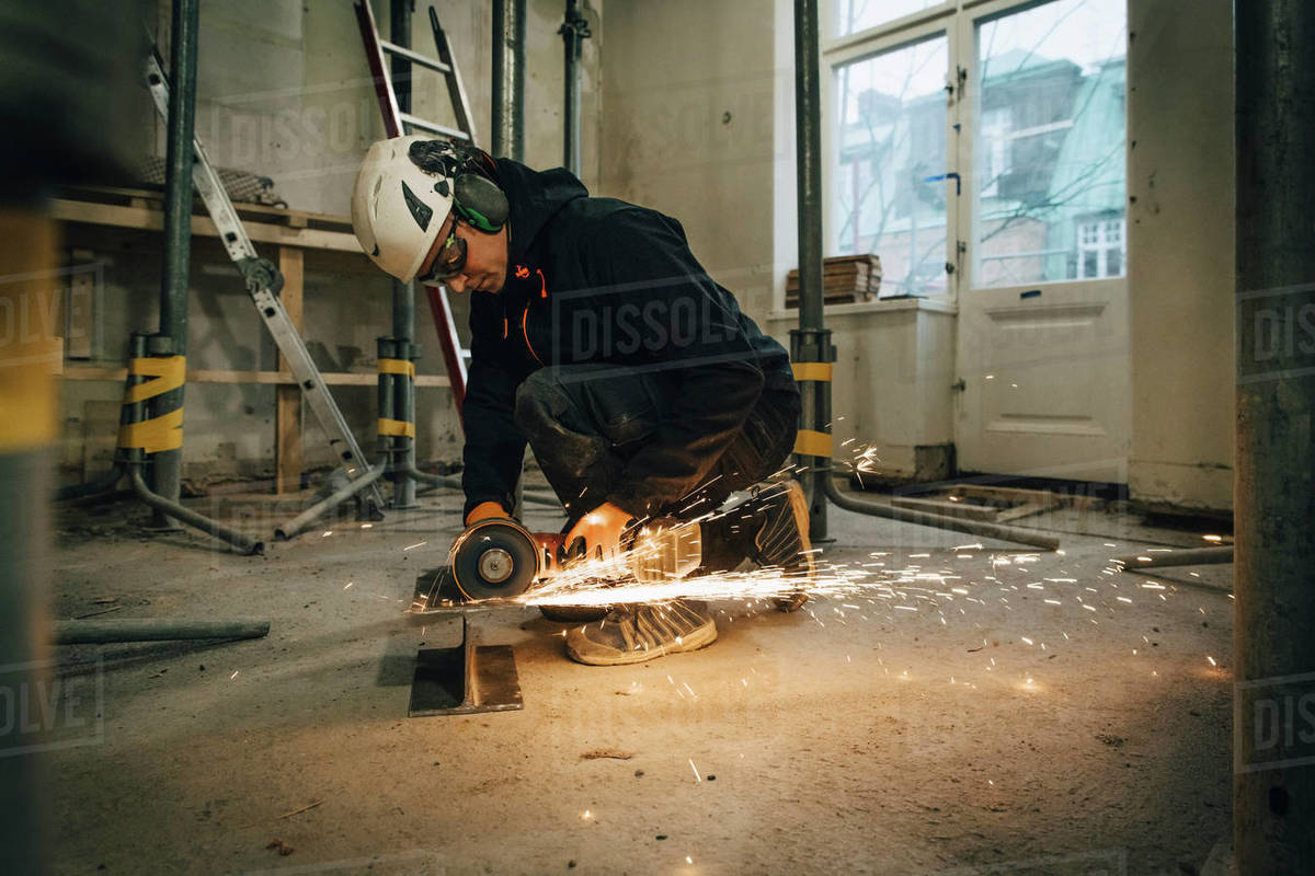 Full length of male construction worker using electric saw while ...