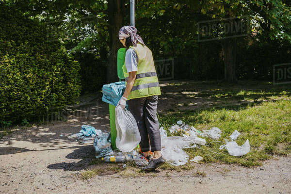 Young female environmentalist throwing plastic waste in garbage bin ...