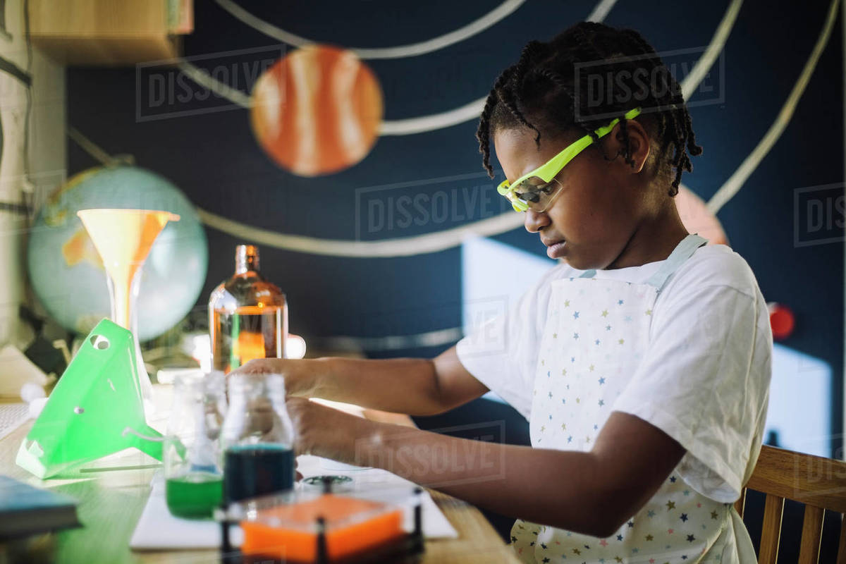 Female student concentrating while doing science project at table ...