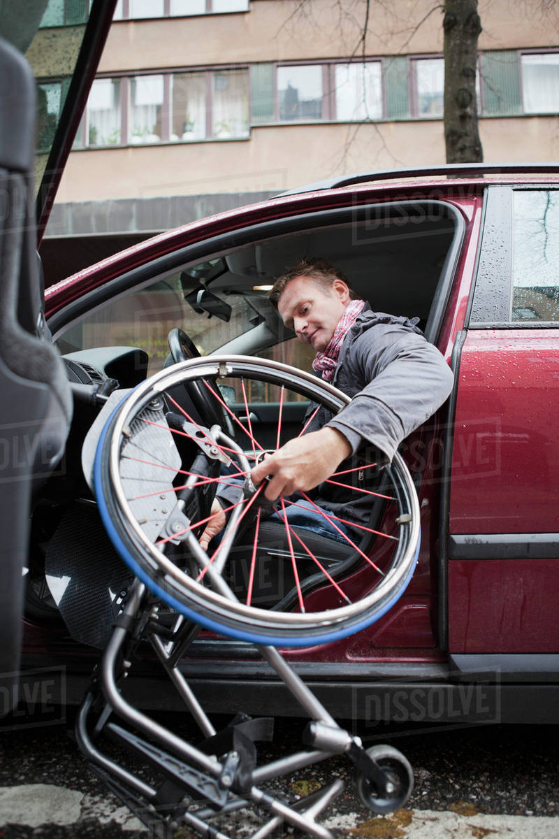 Man lifting wheelchair into car - Royalty-free Stock Photo | Dissolve