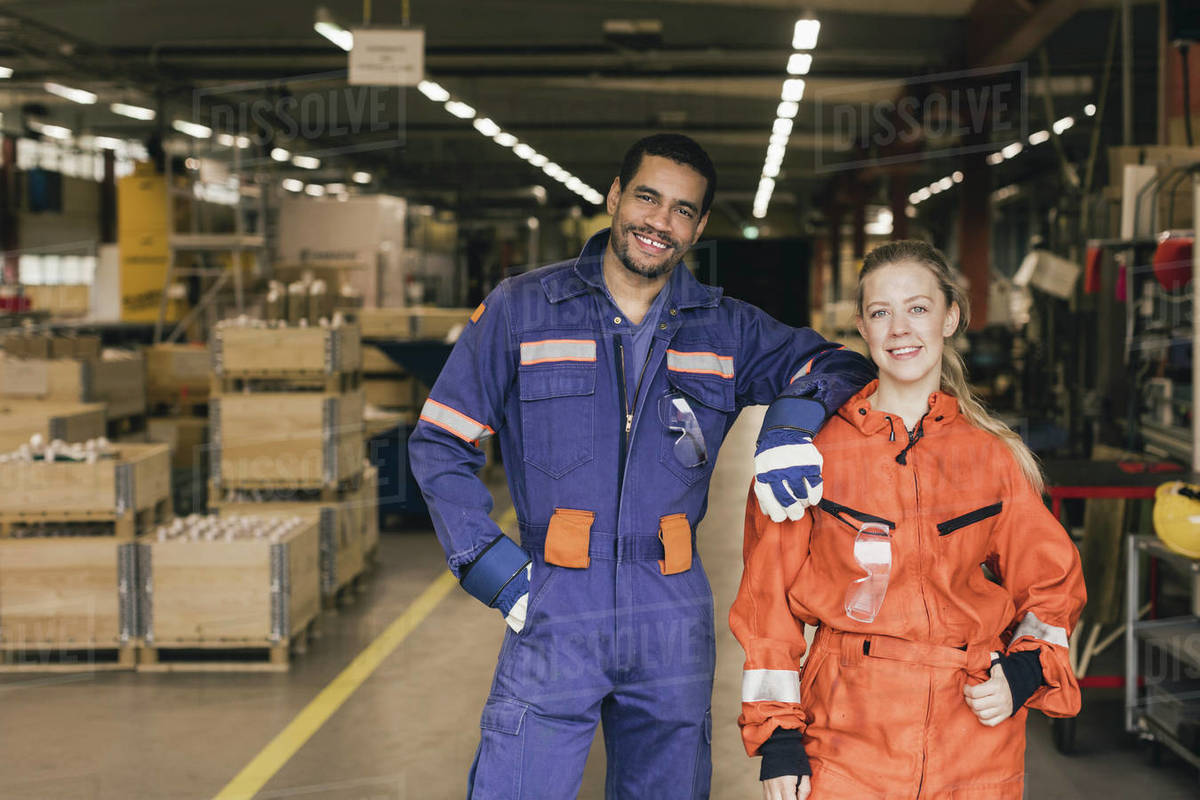Portrait of smiling male and female coworkers in factory warehouse ...