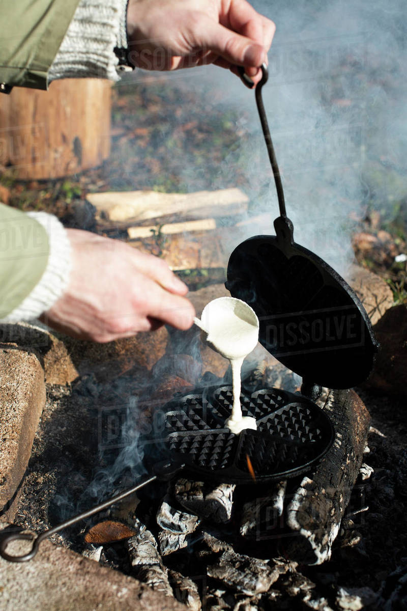 Hands of man pouring batter in waffle maker at bonfire - Royalty-free ...