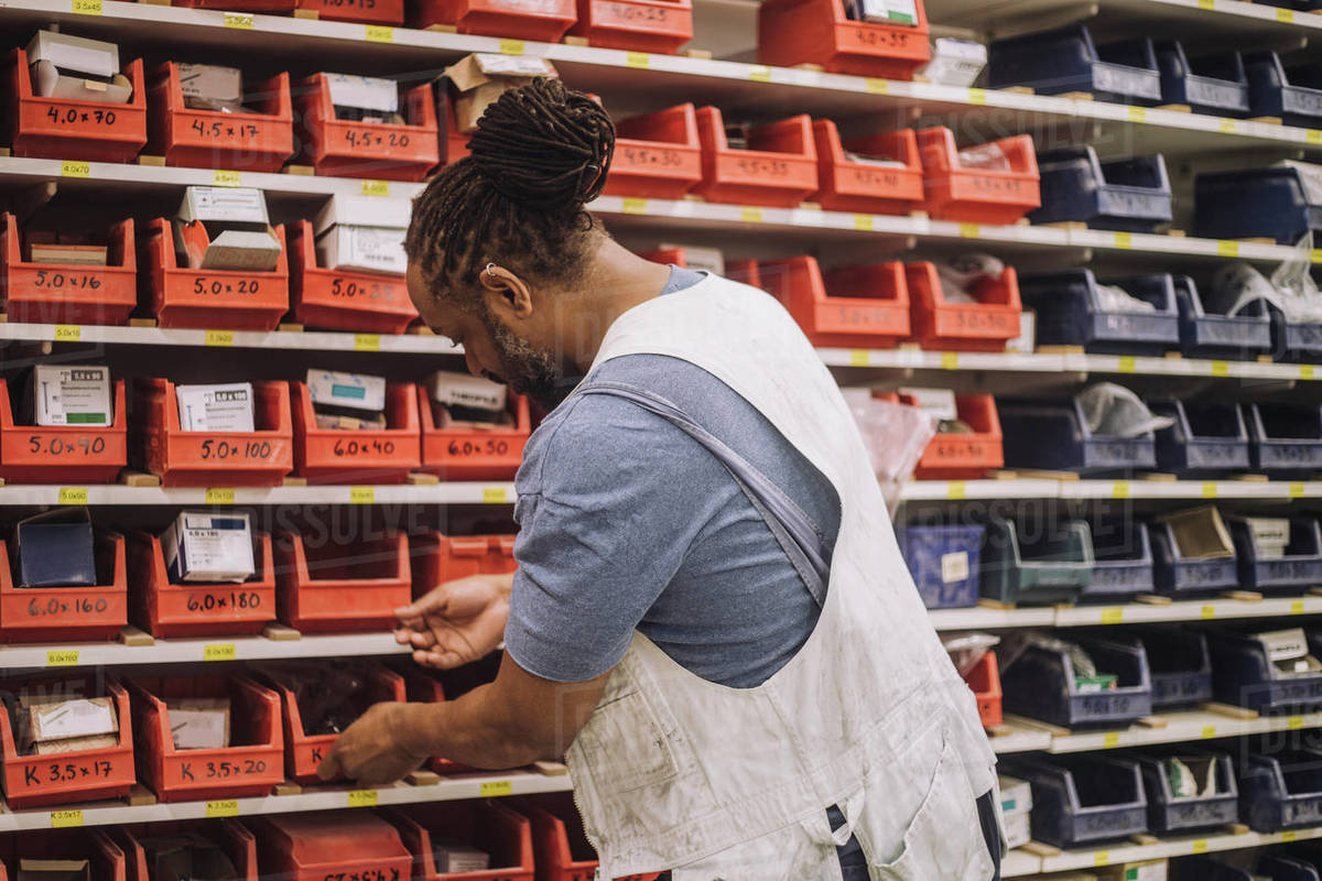 Blue-collar worker searching in containers on rack while working in ...
