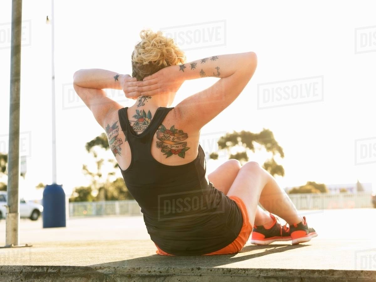 Rear view of young woman doing sit ups in parking lot - Stock Photo ...