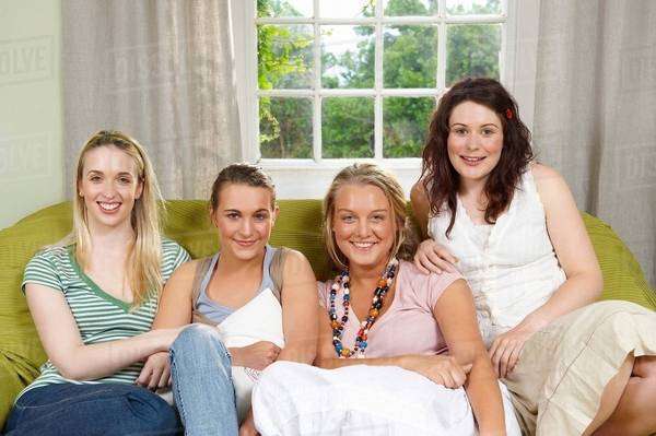 Four young women seated on couch - Royalty-free Stock Photo | Dissolve
