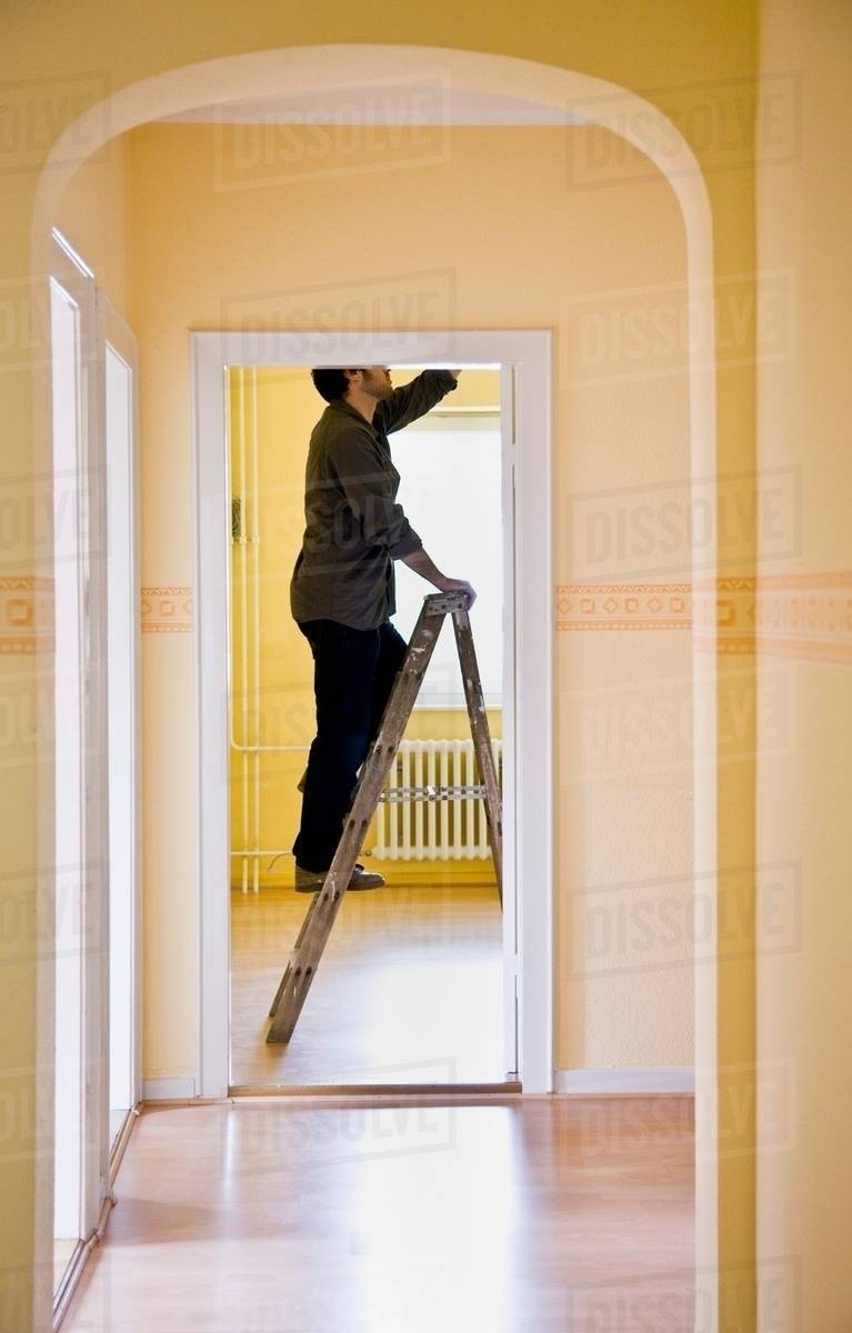 Man changing a light-bulb on a ladder - Royalty-free Stock Photo | Dissolve