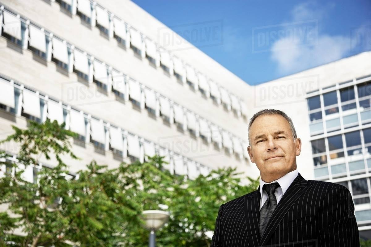 Business man standing, buildings behind - Stock Photo - Dissolve